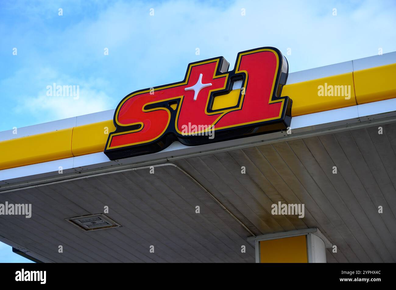 A bold gas station sign displays vibrant colors against a clear blue ...