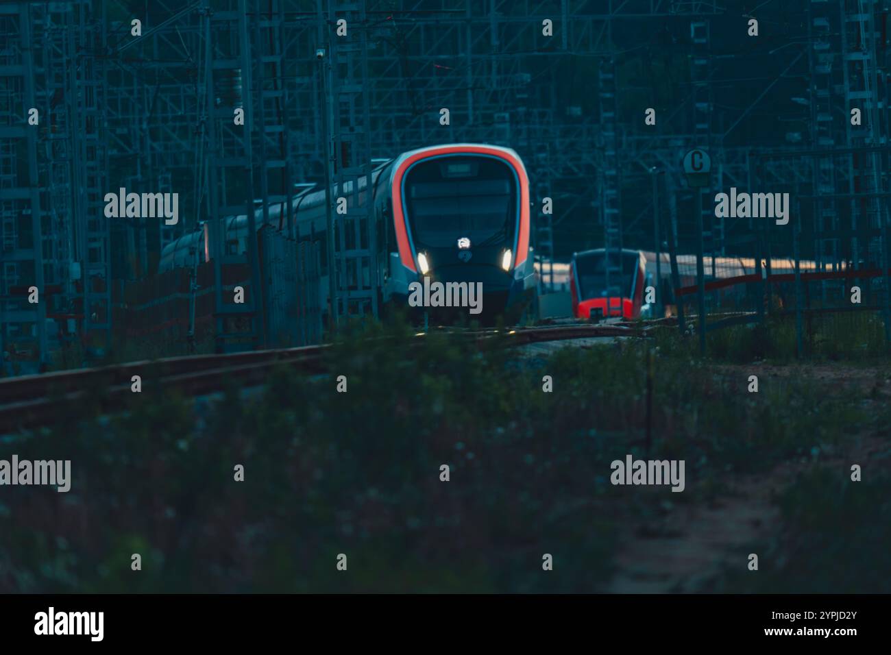 A train approaching a dimly lit station at dusk, with glowing ...