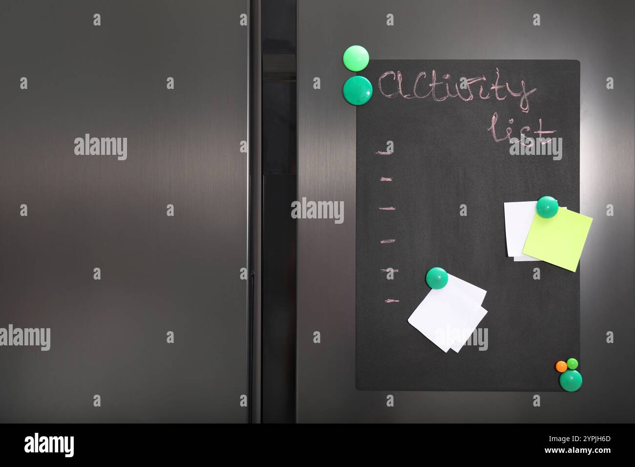 Magnetic board with activity list and notes on refrigerator in kitchen ...