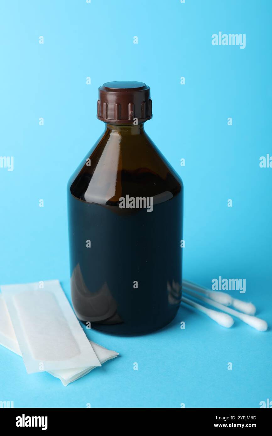 Topical iodine, cotton swabs and adhesive bandages on light blue ...