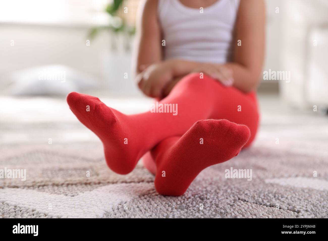 Child in red tights sitting on floor at home, closeup Stock Photo - Alamy