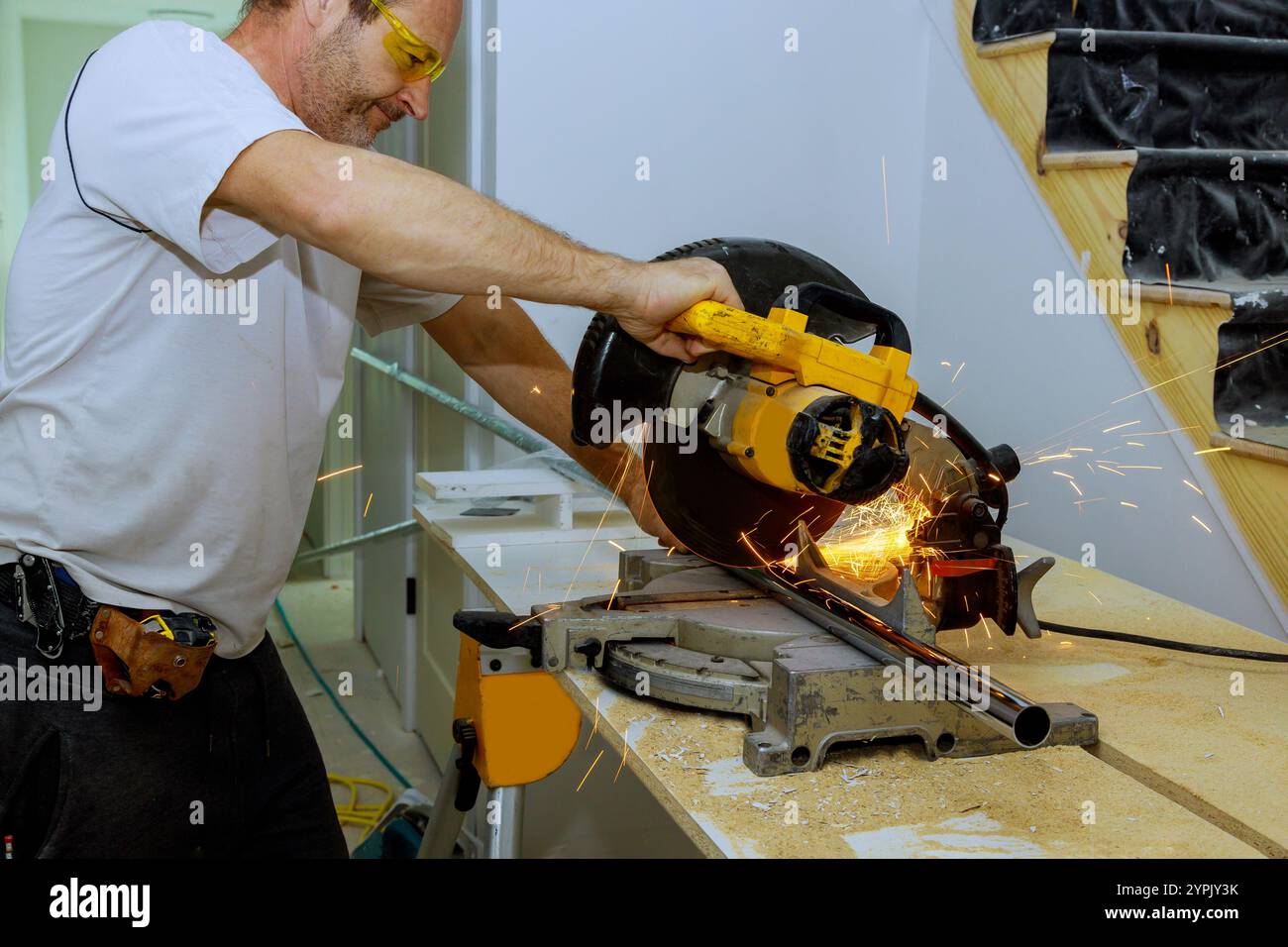 Worker operates power saw to precisely cut metal pipe amidst sparks fly ...