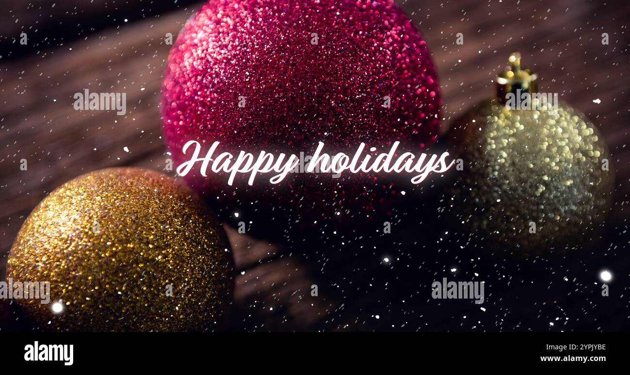 Image of happy holidays text and snow falling over christmas baubles ...