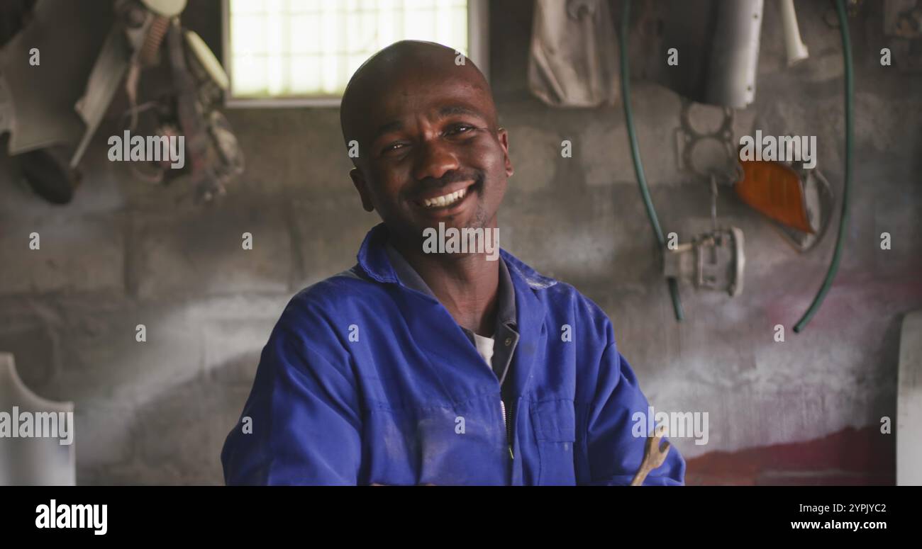 Portrait of a happy African male panel beater in a township workshop ...