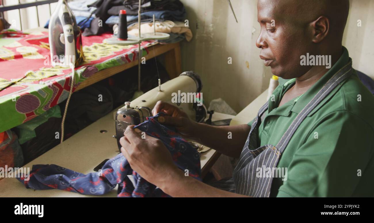 Side view high angle of an African male tailor in a township workshop ...