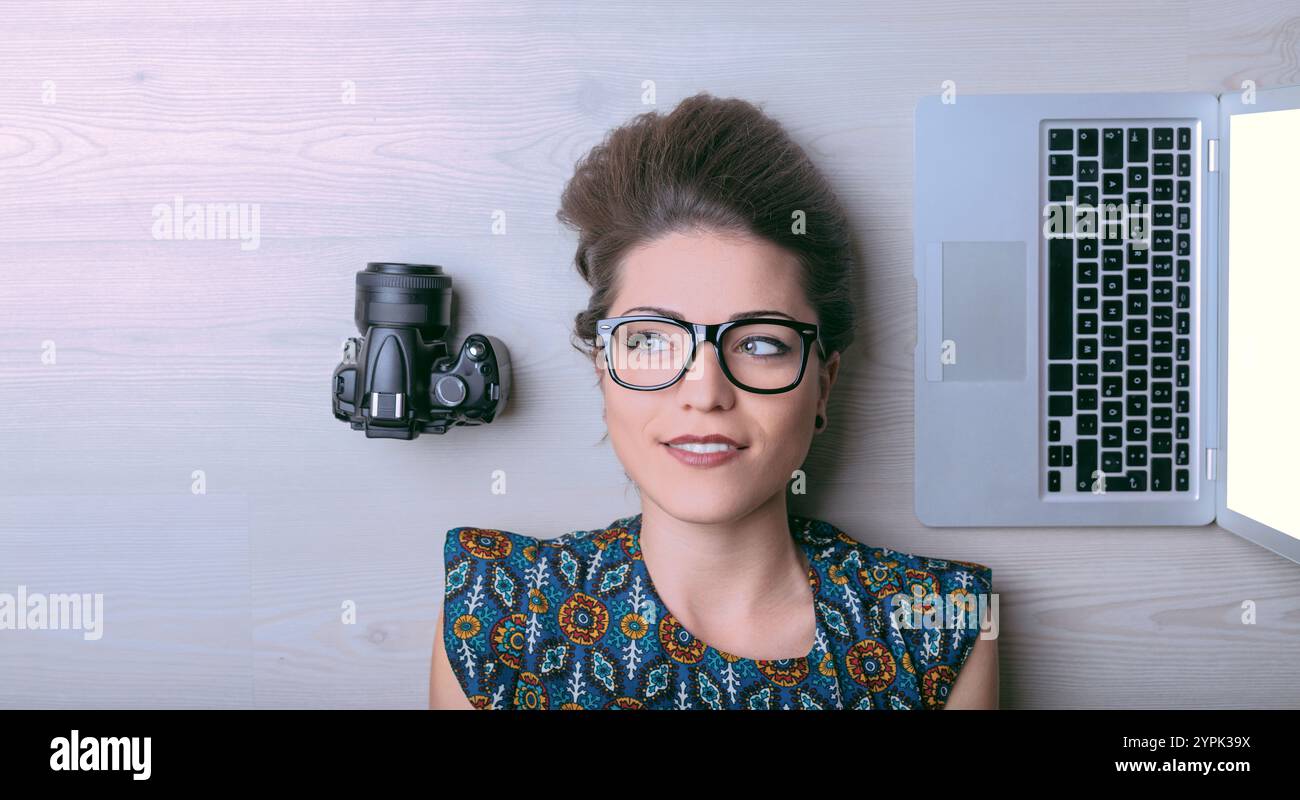 Young female photographer lying on a wooden floor with her camera and ...