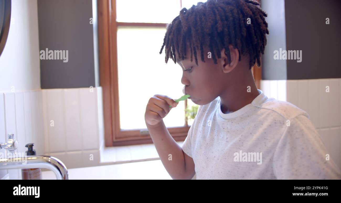 African american boy brushing teeth in bathroom at home, slow motion ...