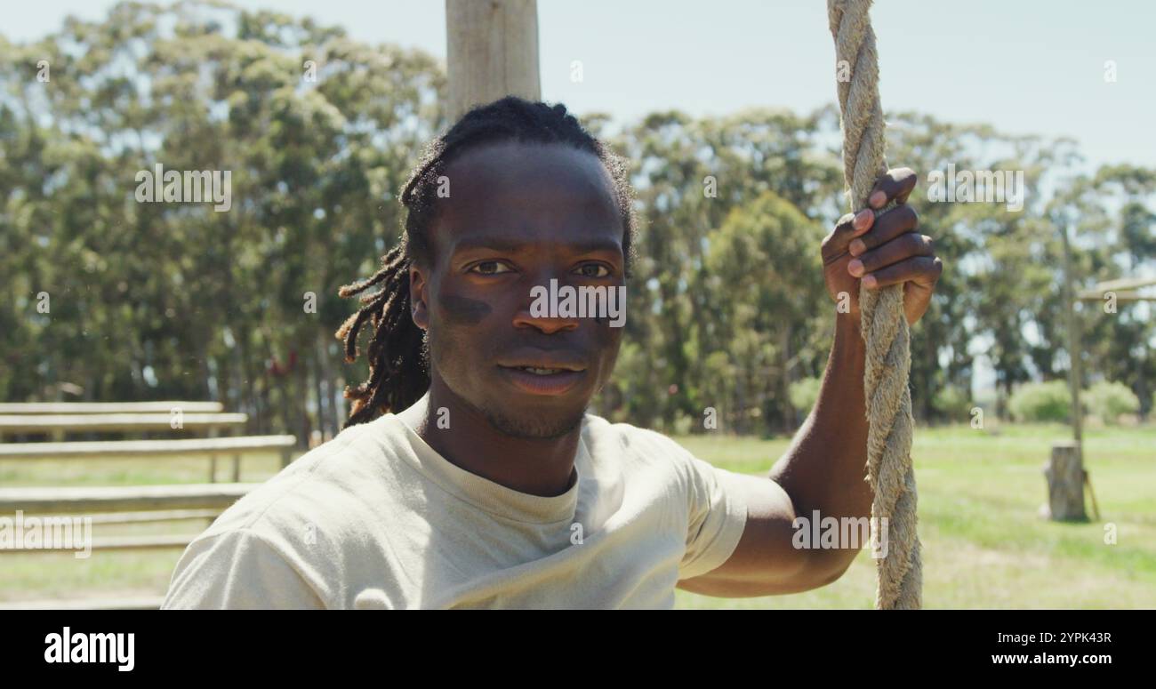 Fit african american male soldier with deadlocks climbing down rope on ...