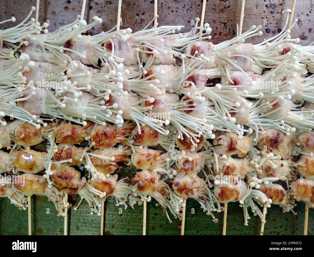 Grilled cooked Enoki mushroom wrapped in bacon on a bamboo skewer ...