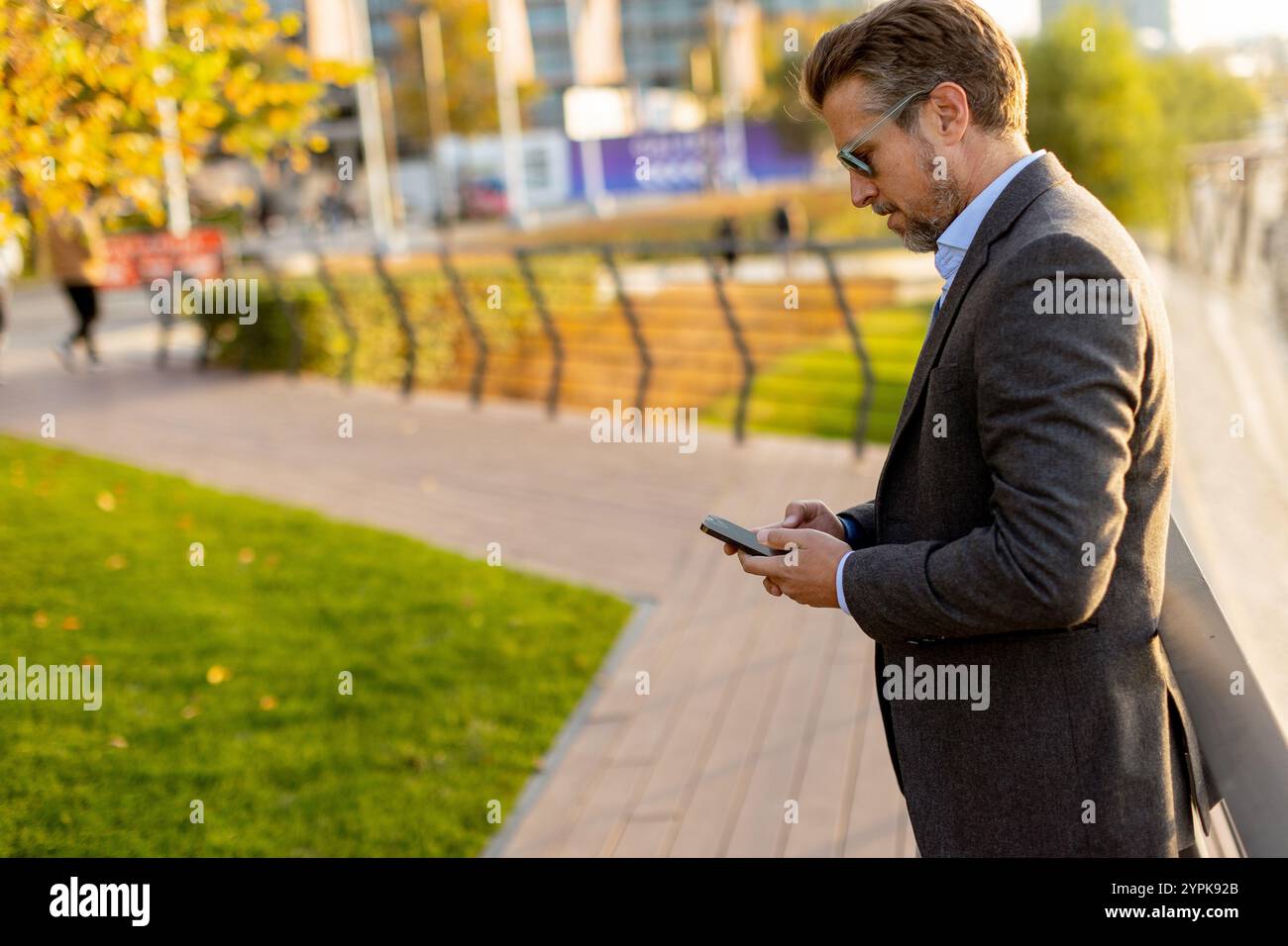 Dressed in smart casual attire, a man stands by an urban landscape ...