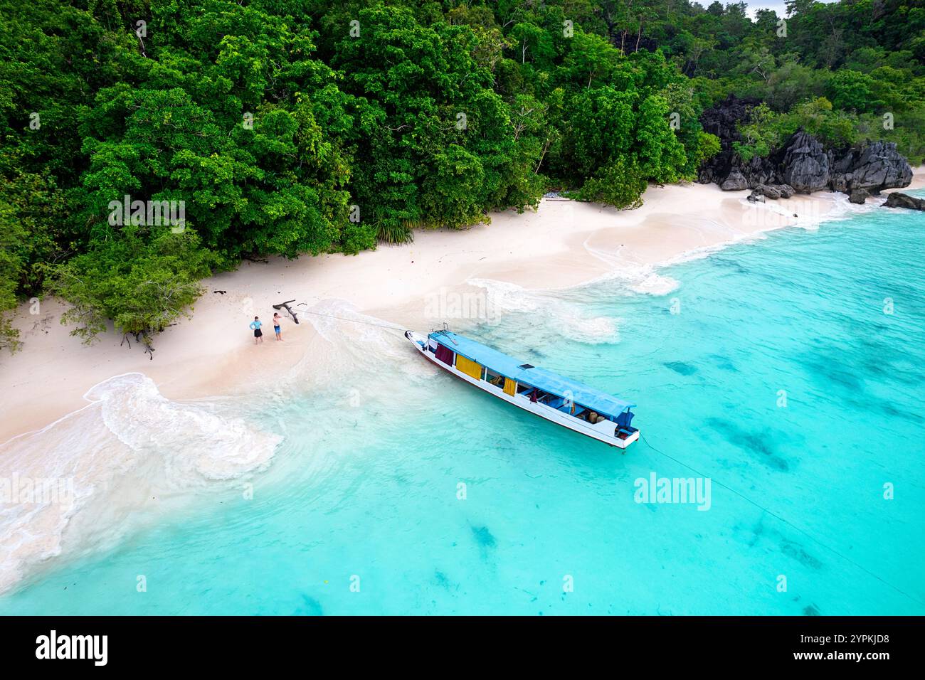Aerial view of tourists and a fishing boat on secluded white sandy ...