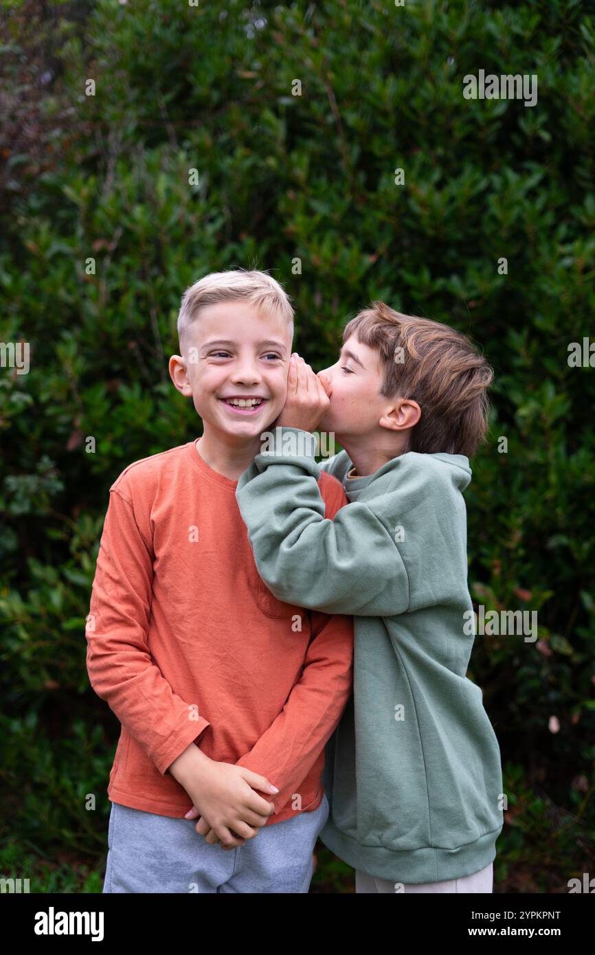 A child telling a secret to another child outdoors Stock Photo - Alamy