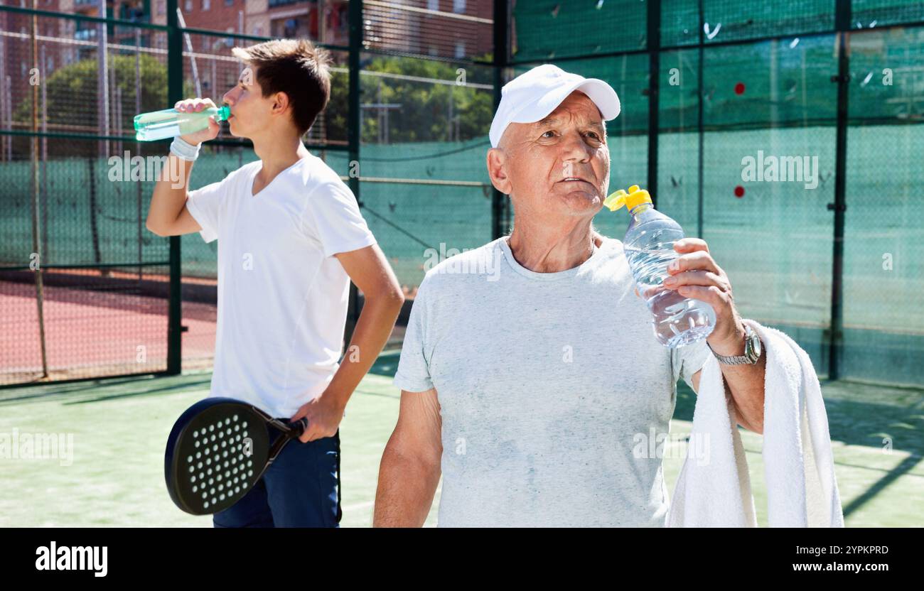 Padel players of different generations drink water on padel court Stock ...