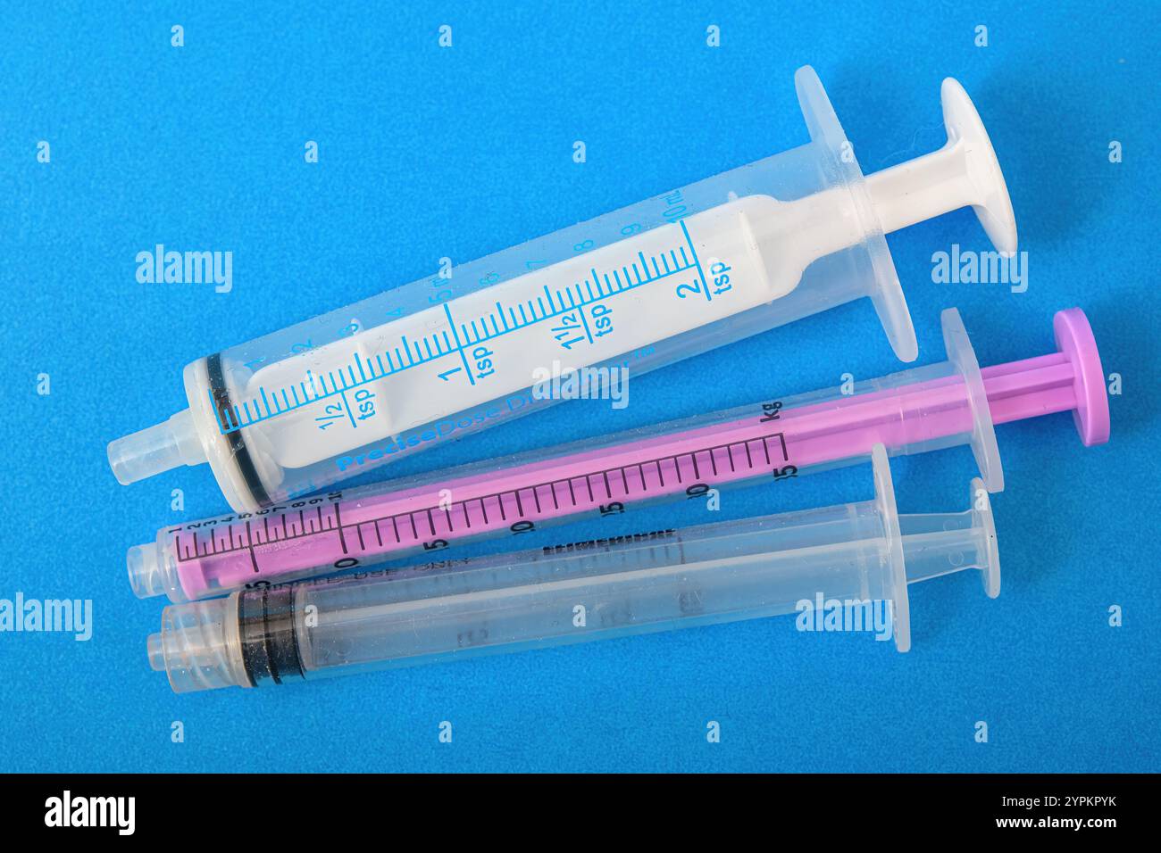 Three types of disposable plastic syringes against a blue background ...