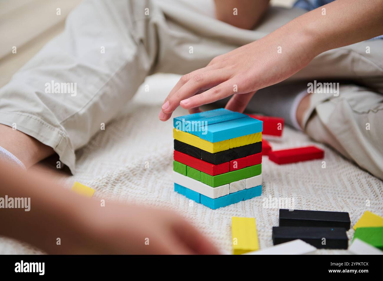 Two children are playing with colorful blocks, stacking them carefully ...