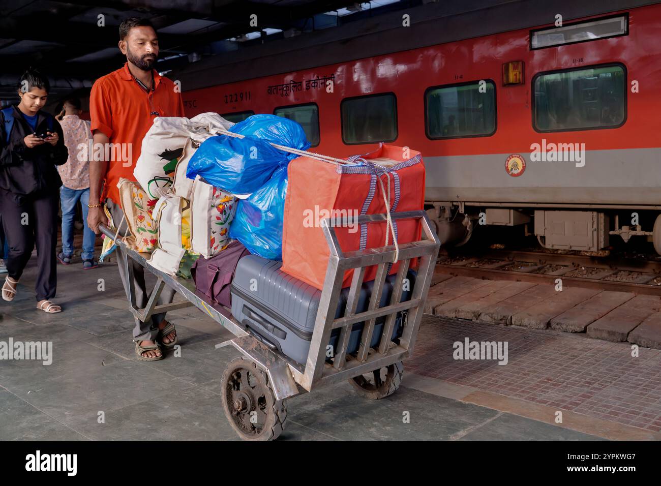 An Indian railway porter pushes a trolley fully loaded with luggage ...