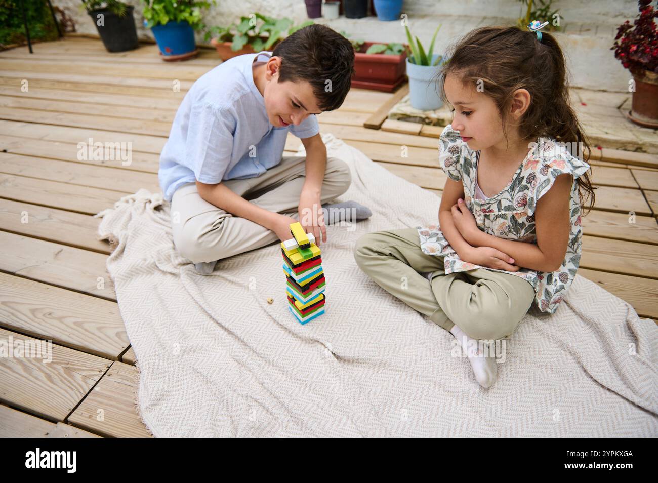 Two children focus intently on stacking colorful blocks on a wooden ...