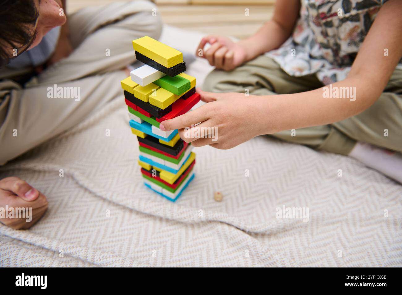 Two children engage in a playful block stacking game. Their hands ...