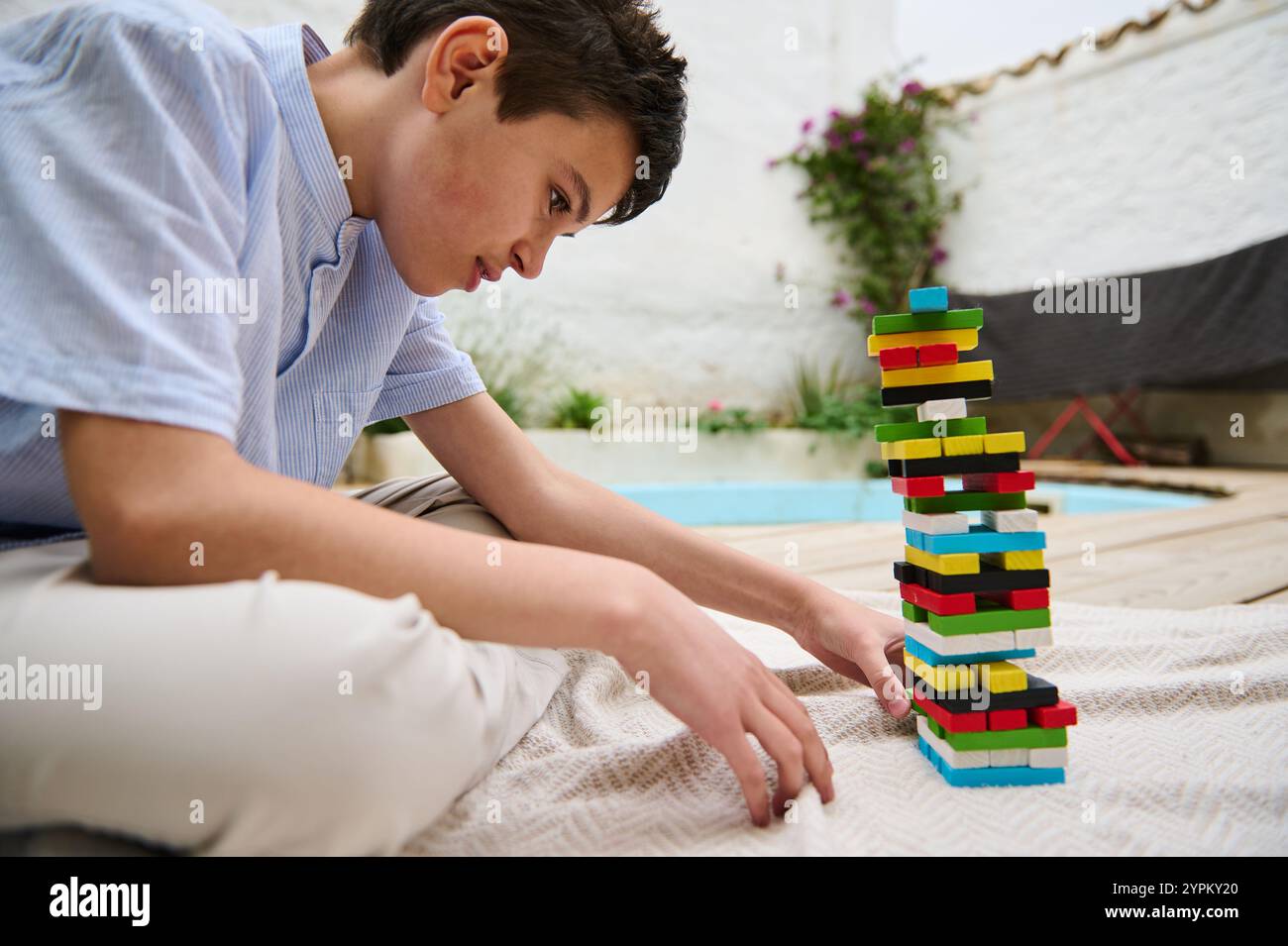 A young boy intently builds a vibrant block tower, demonstrating focus ...
