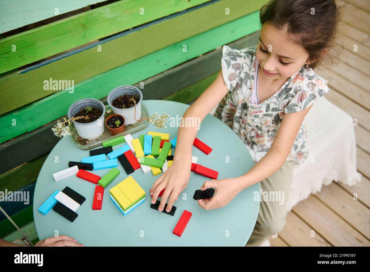 A young girl happily engages with colorful blocks at a small round ...
