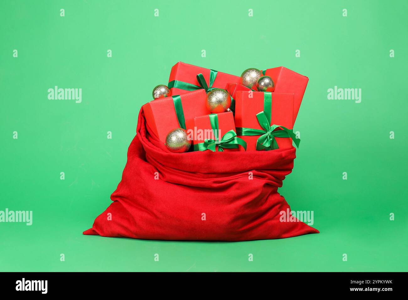 Red Santa Claus bag with baubles and gift boxes on green background ...