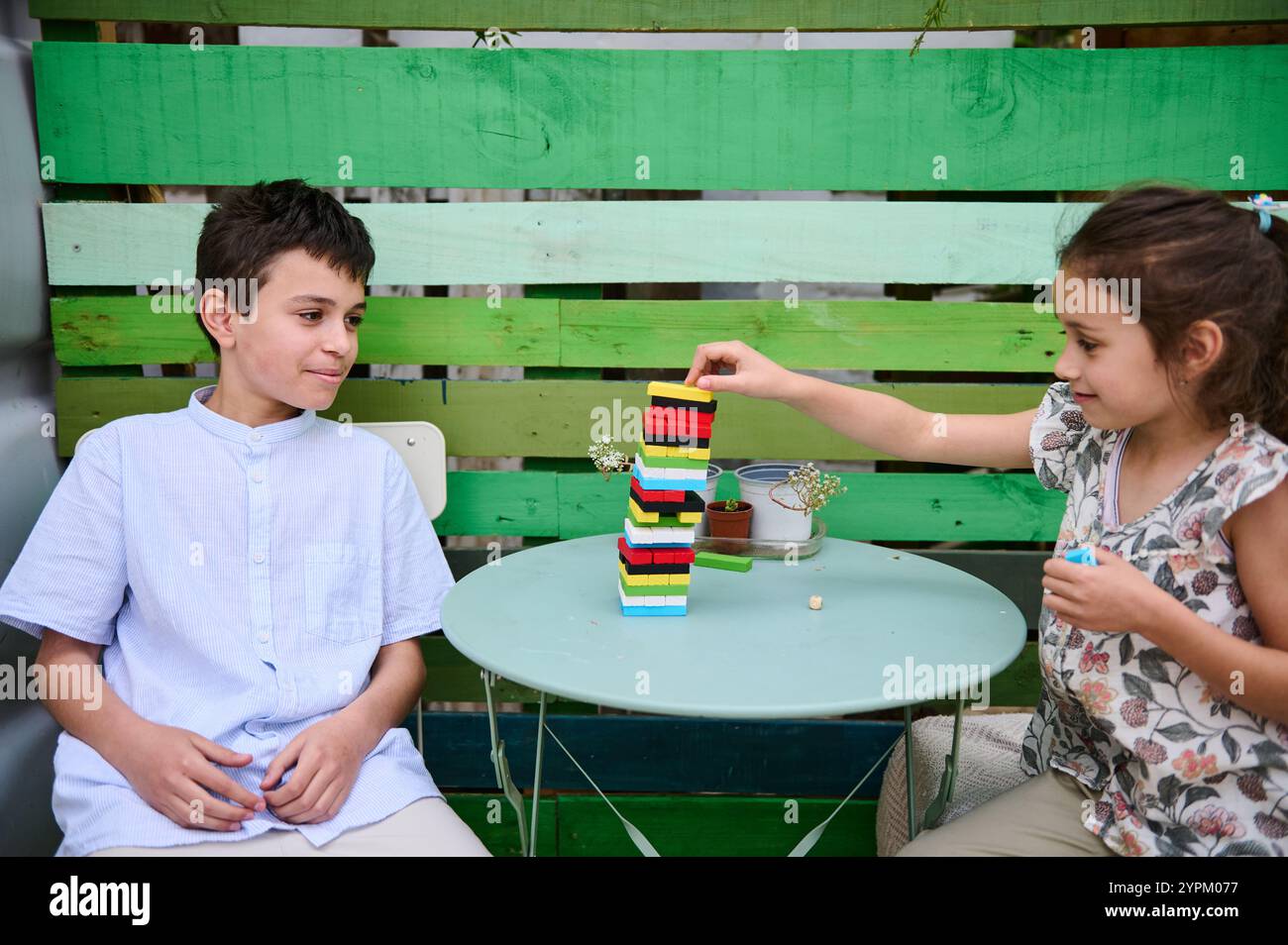 Two children enjoying a playful activity by stacking colorful blocks on ...