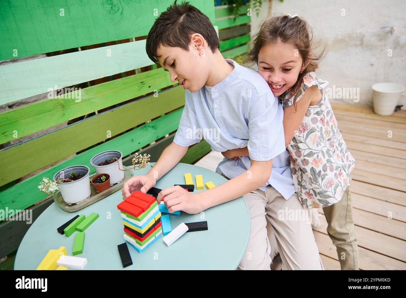Two happy siblings enjoy playing with colorful building blocks outdoors ...