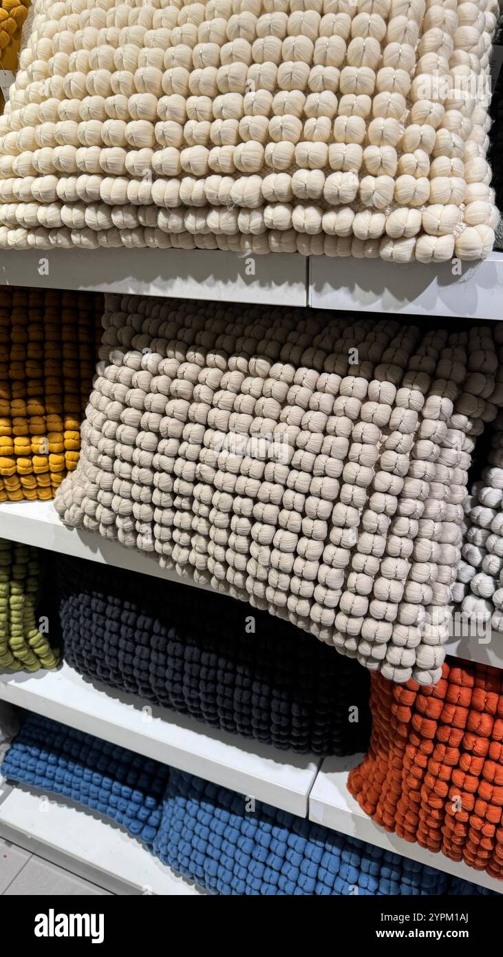 A close-up shot shows multiple textured throw pillows stacked on white ...