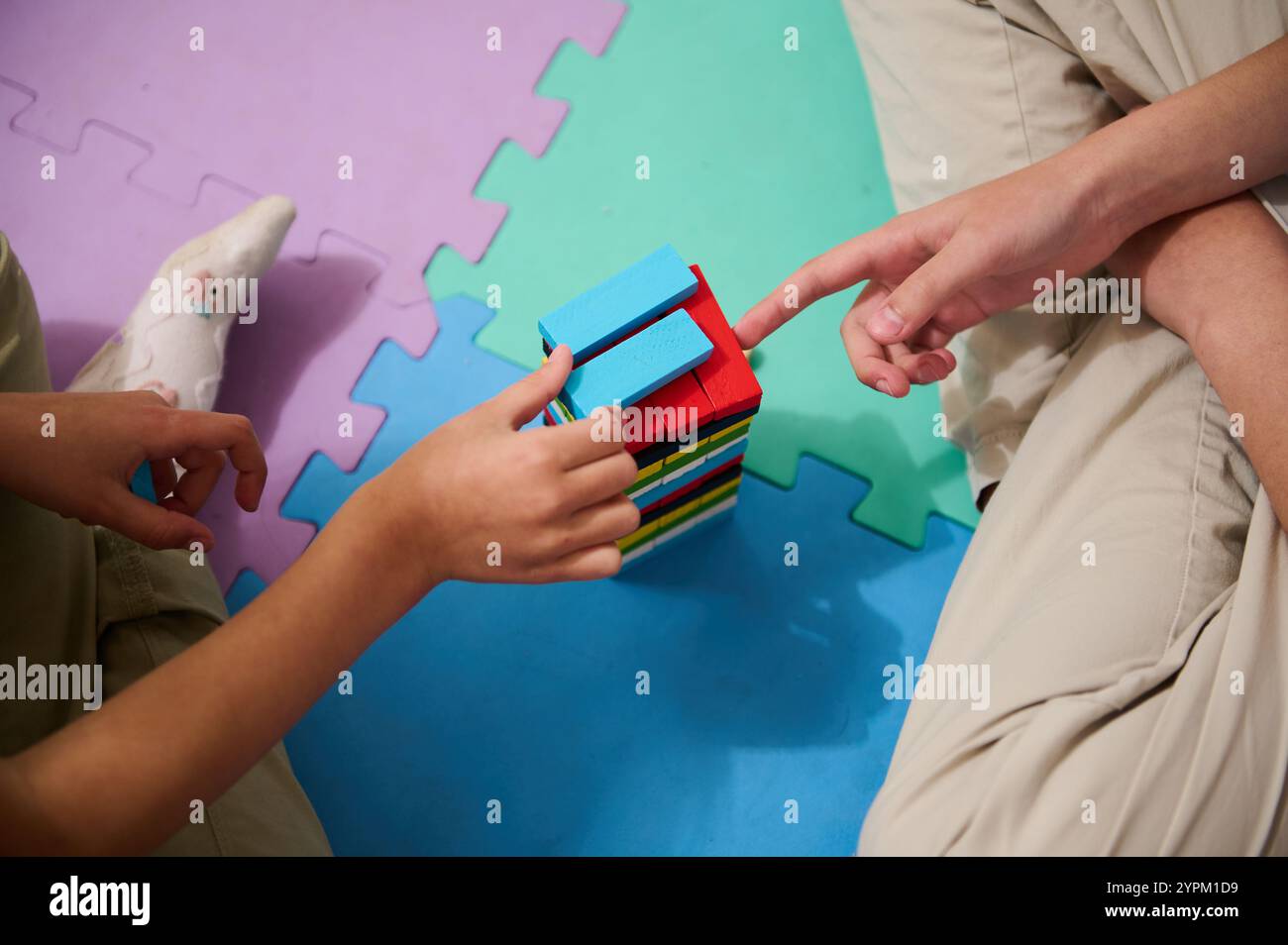 Two children are engaged in a playful moment, stacking colorful blocks ...