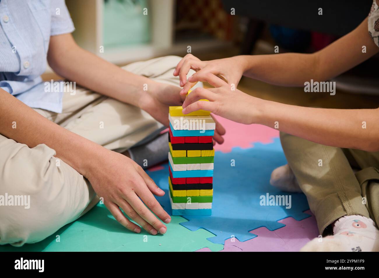 Two children are engaged in stacking vibrant blocks on a padded ...