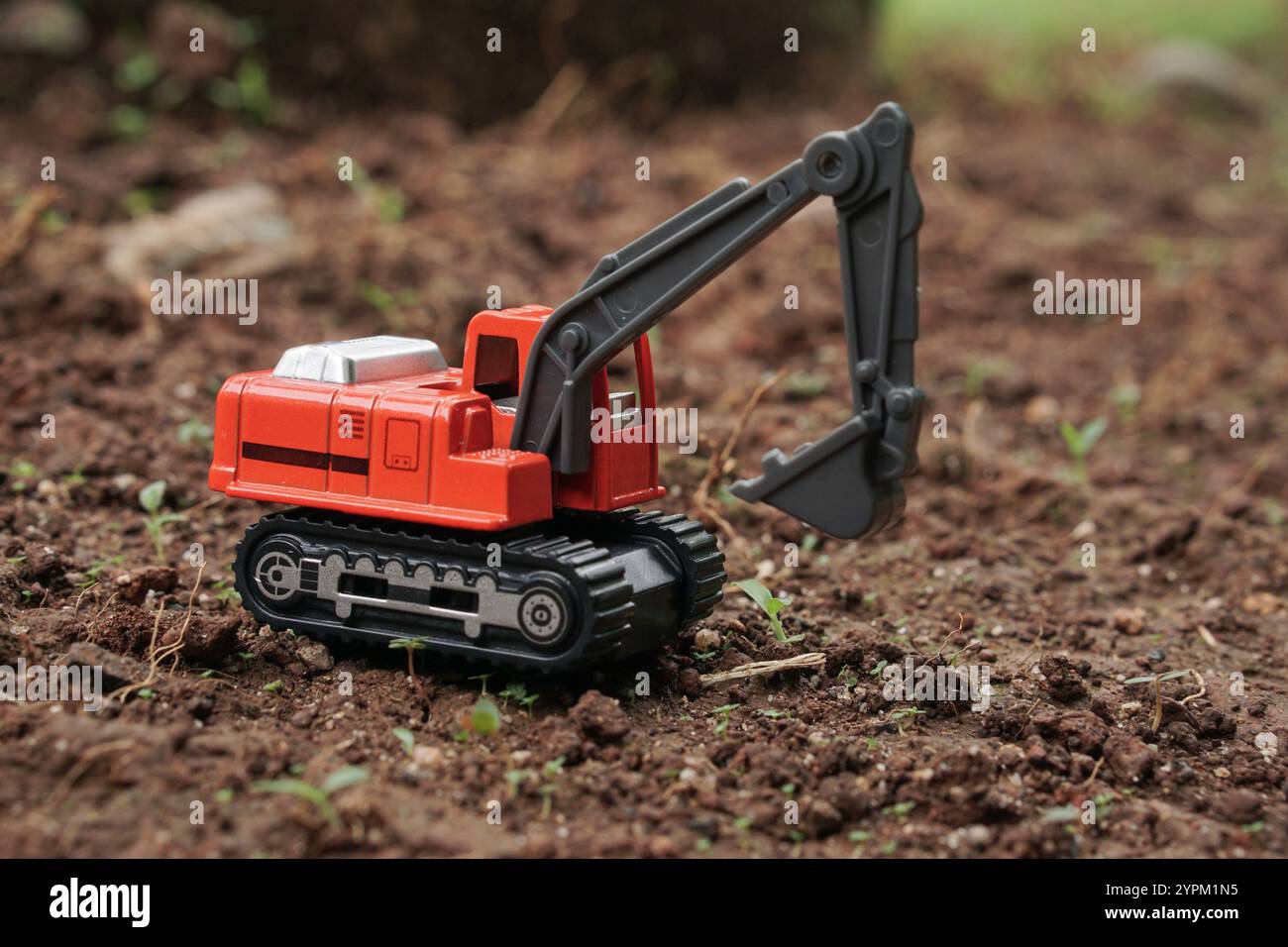 Orange excavator or digger toy excavate on a soil land outdoor. model ...