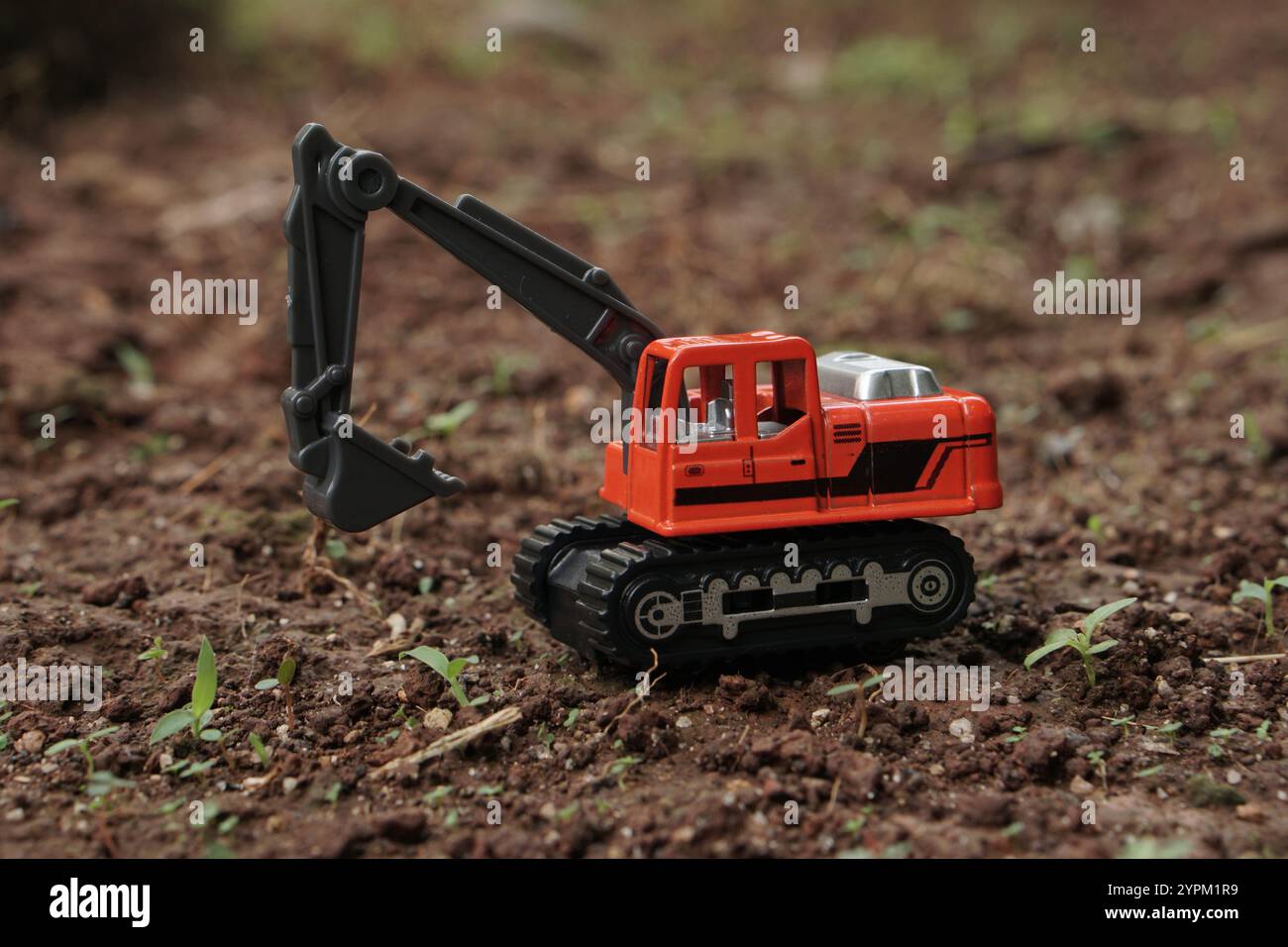 Orange excavator or digger toy excavate on a soil land outdoor. model ...