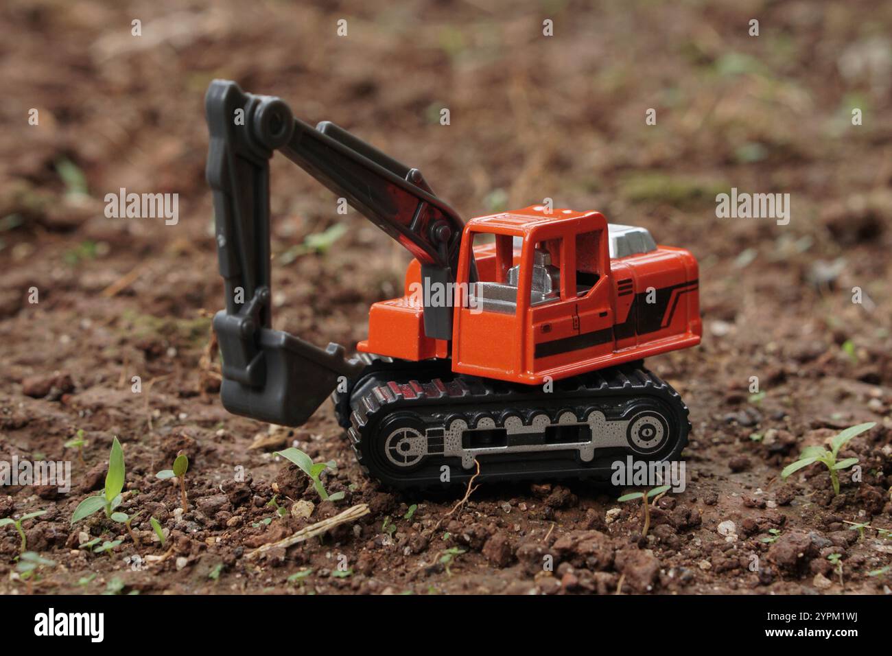 Orange excavator or digger toy excavate on a soil land outdoor. model ...
