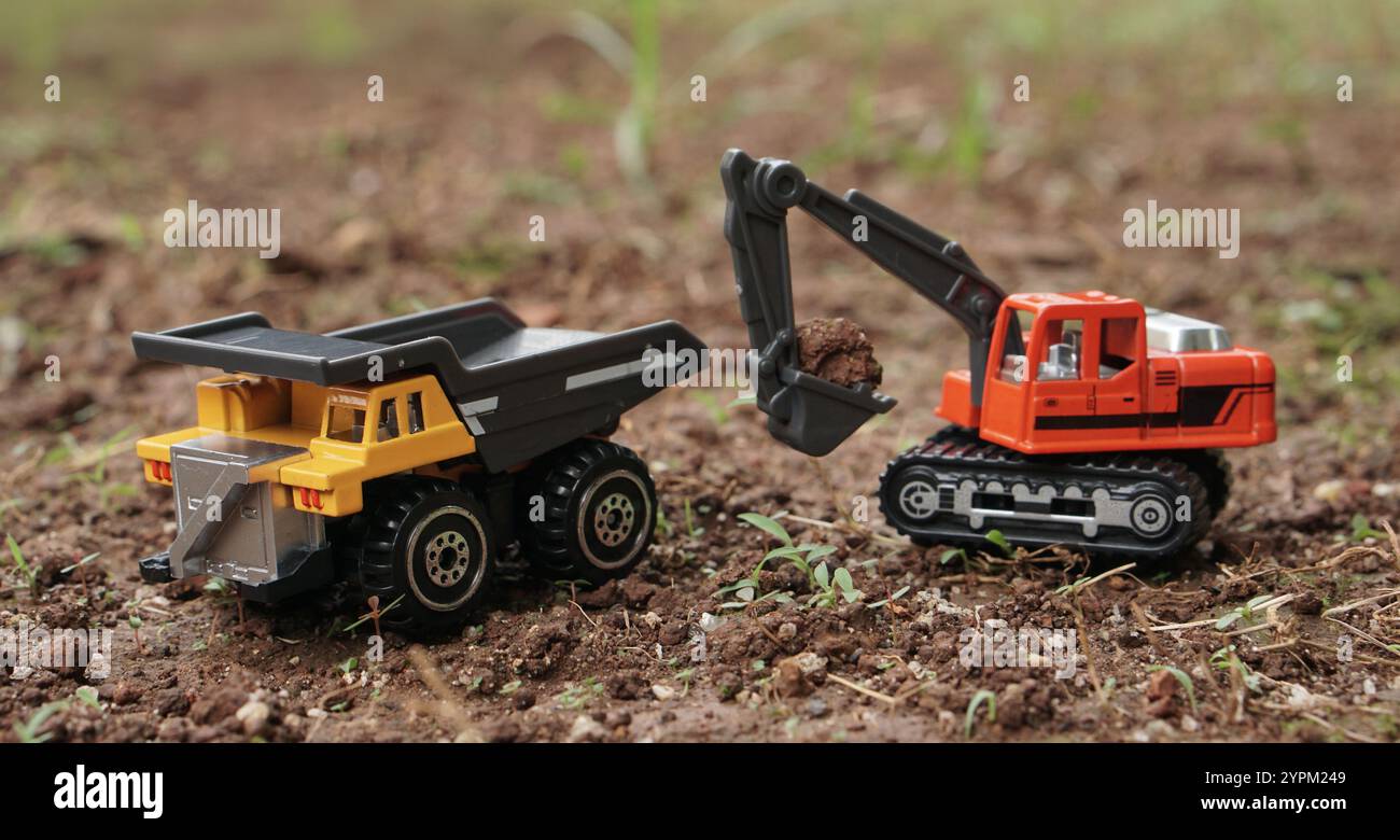 Excavator toy loading a soil to dump truck at outdoor ground ...
