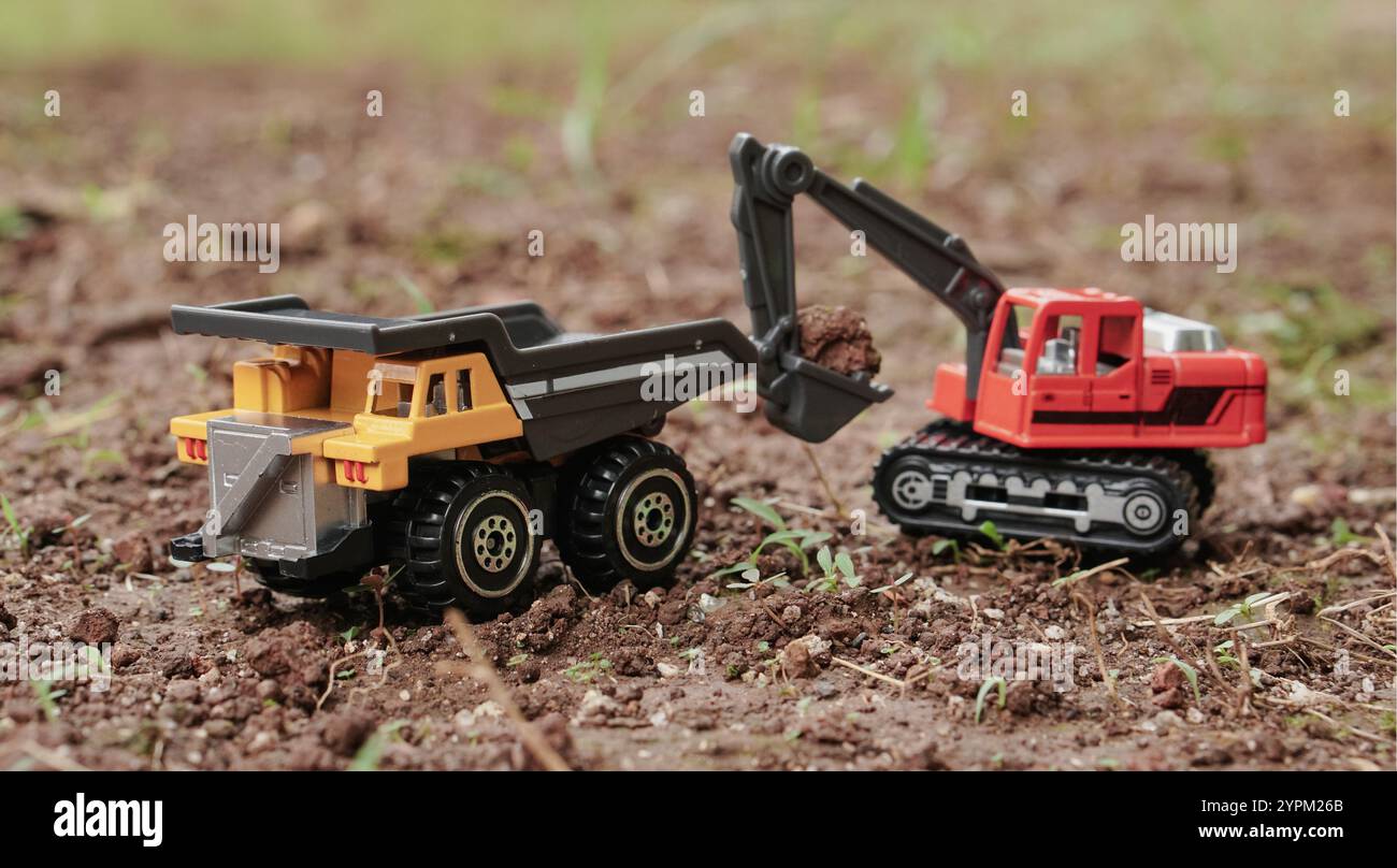 Excavator toy loading a soil to dump truck at outdoor ground ...