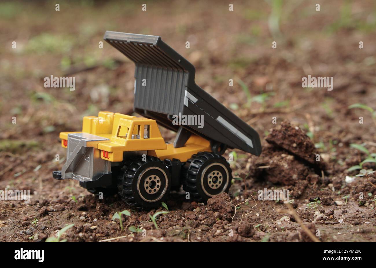 side view of yellow small dump truck toy model dumping soil on the ...