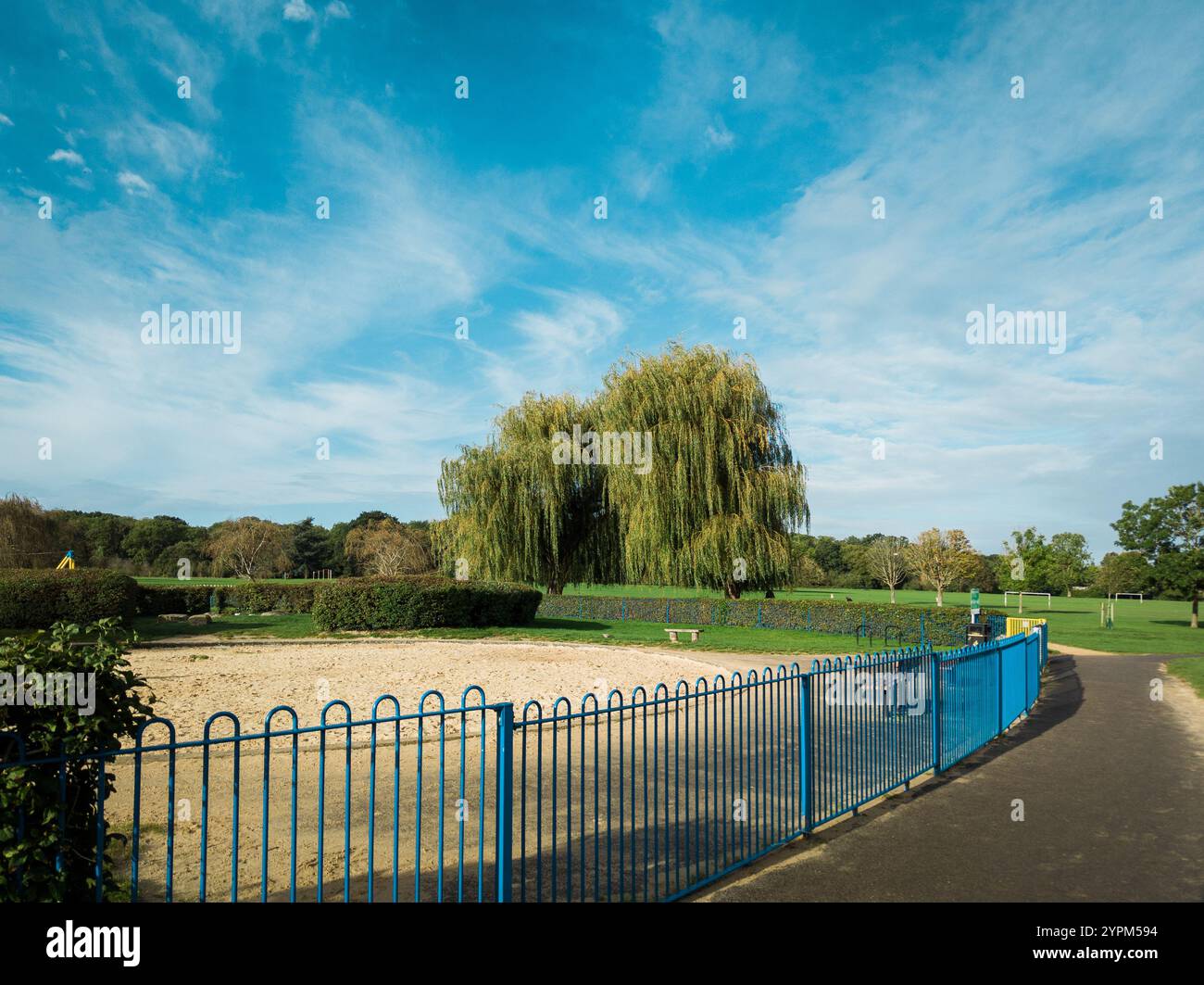 Sunny Park with Blue Fenced Playground, Lush Greenery, and a Majestic ...