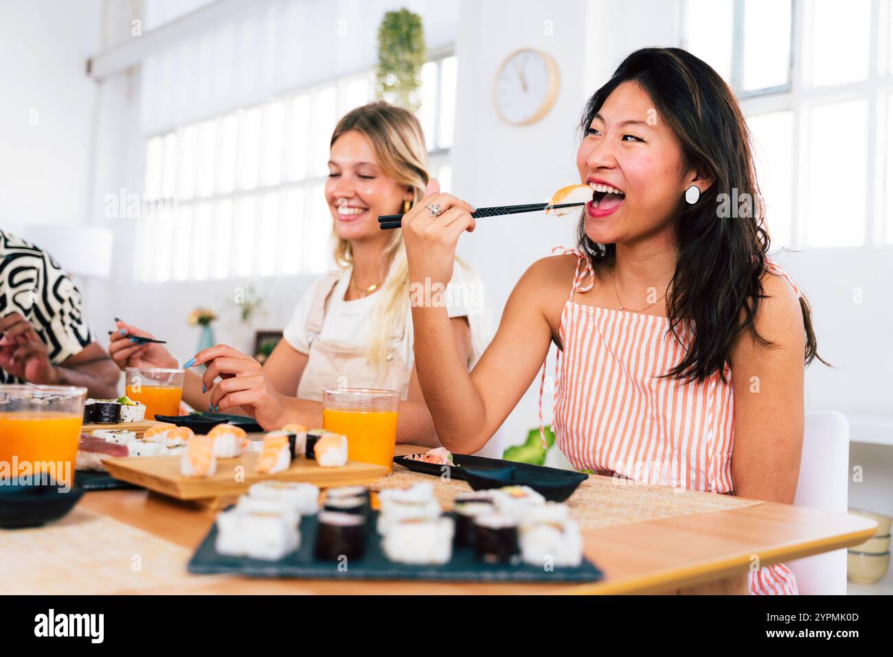 Multiethnic group of young friends meeting at home and eating sushi ...
