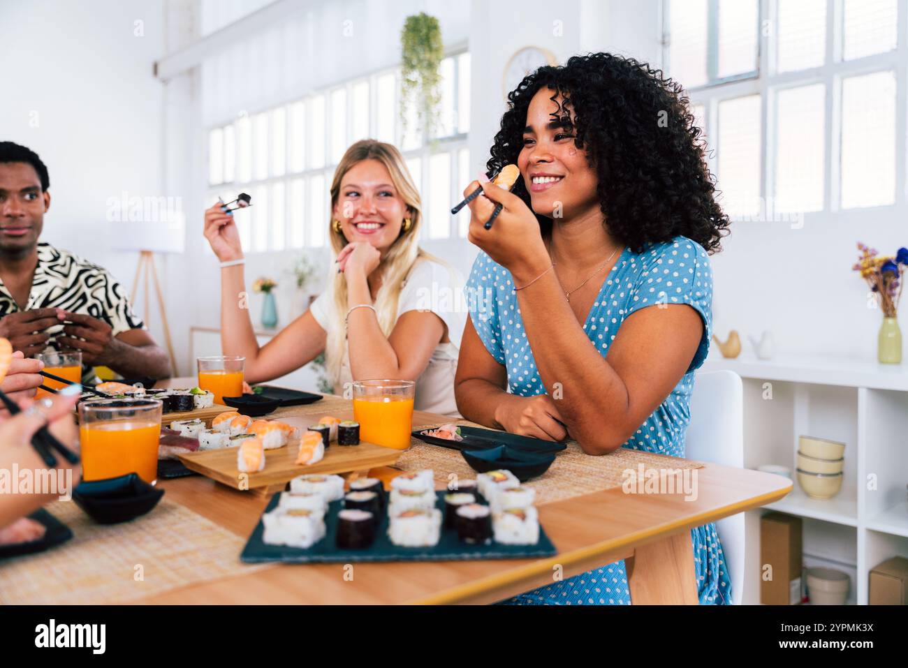 Multiethnic group of young friends meeting at home and eating sushi ...