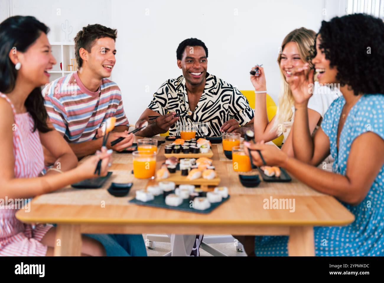 Multiethnic group of young friends meeting at home and eating sushi ...