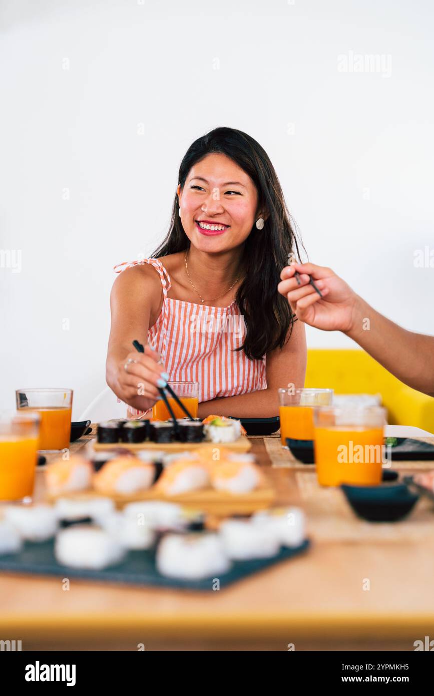 Multiethnic group of young friends meeting at home and eating sushi ...