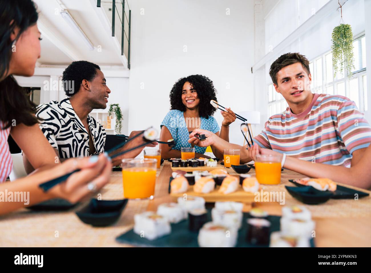 Multiethnic group of young friends meeting at home and eating sushi ...