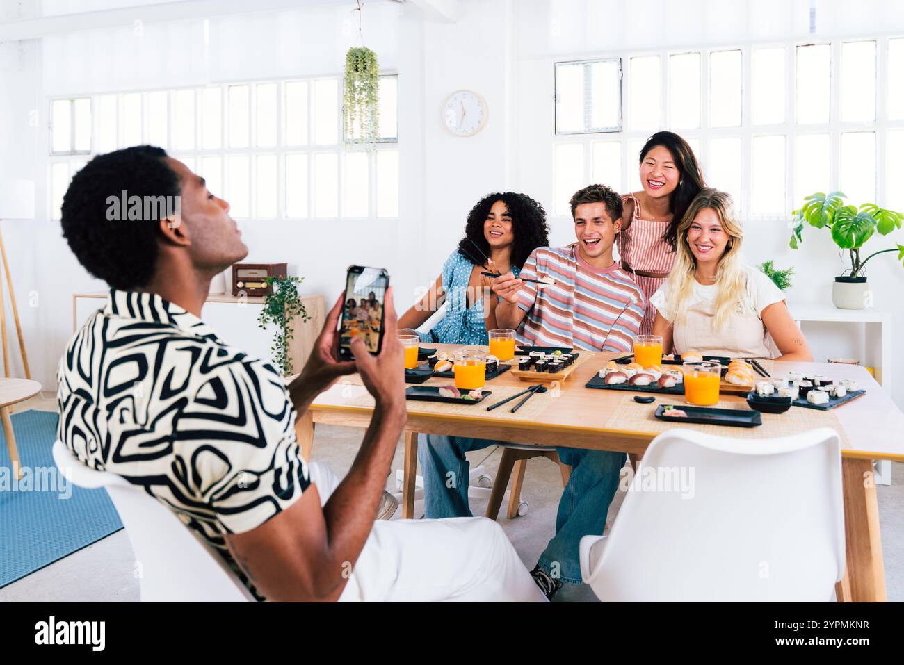 Multiethnic group of young friends meeting at home and eating sushi ...