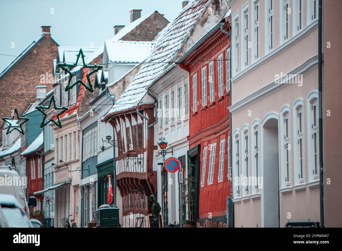 Snow-covered Scandinavian streets in Odense, Denmark, featuring colorful traditional Danish ...