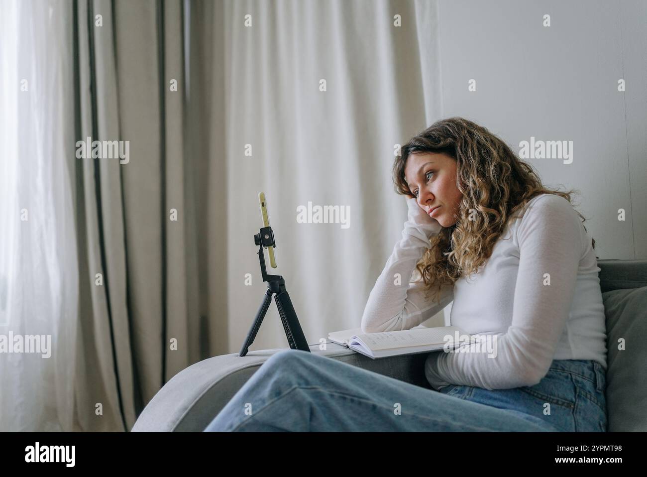 Tired woman attends an online class in her cozy living room, showing ...