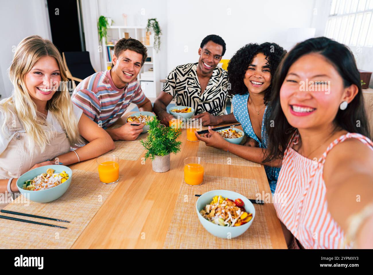 Multiethnic group of young friends meeting at home and eating poke ...