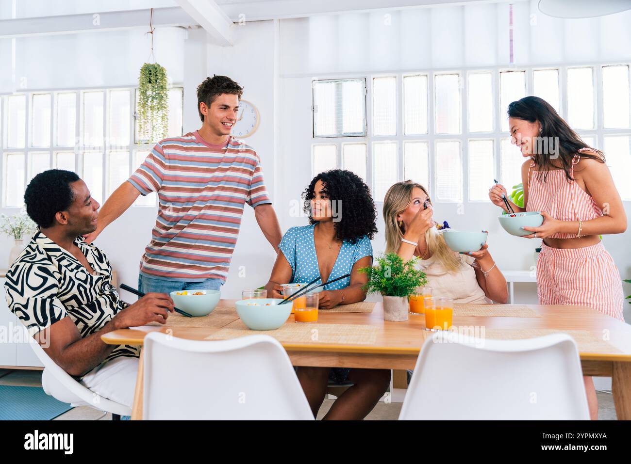 Multiethnic group of young friends meeting at home and eating poke ...