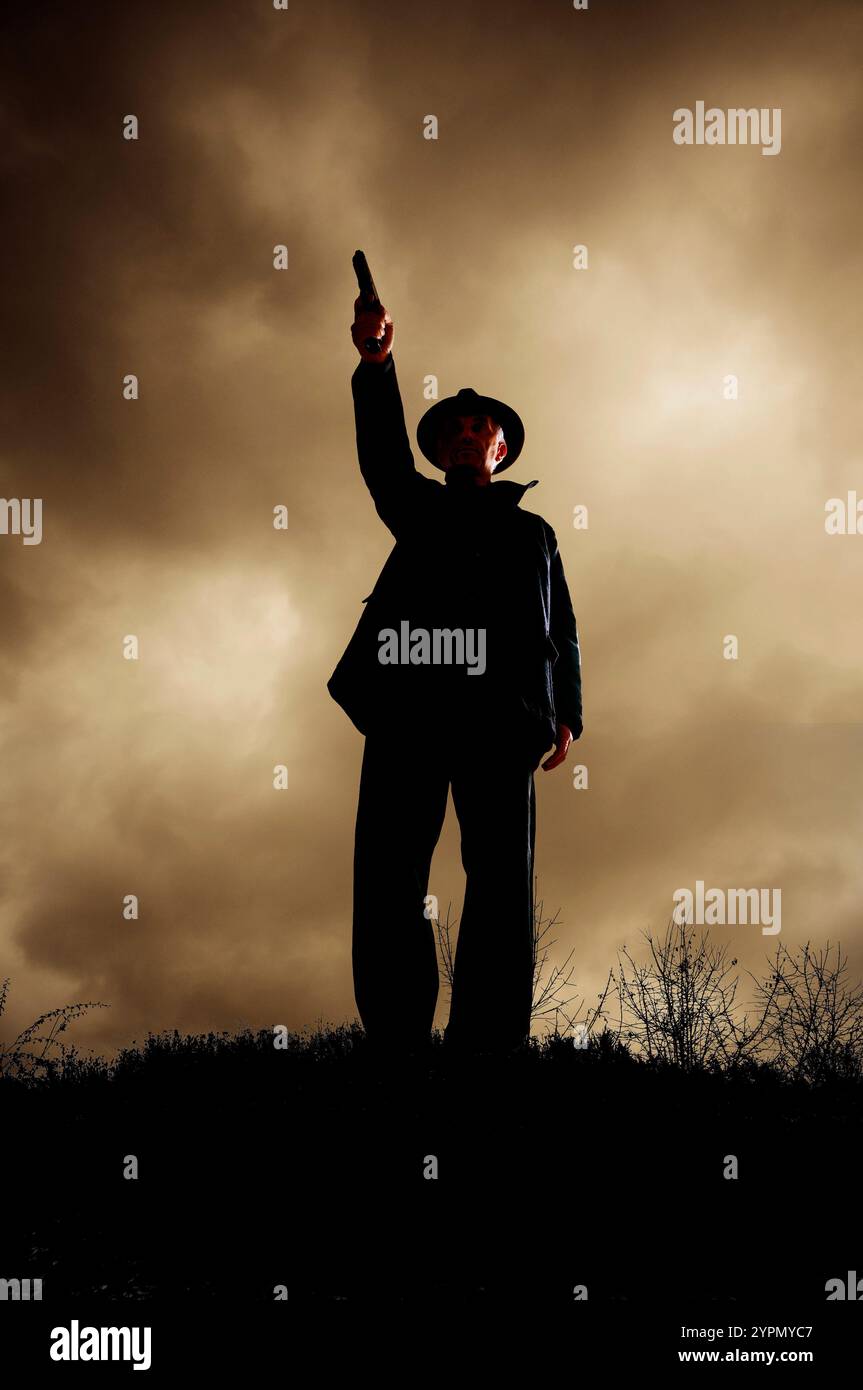 man standing on a cliff edge and pointing a gun, low angle view Stock ...