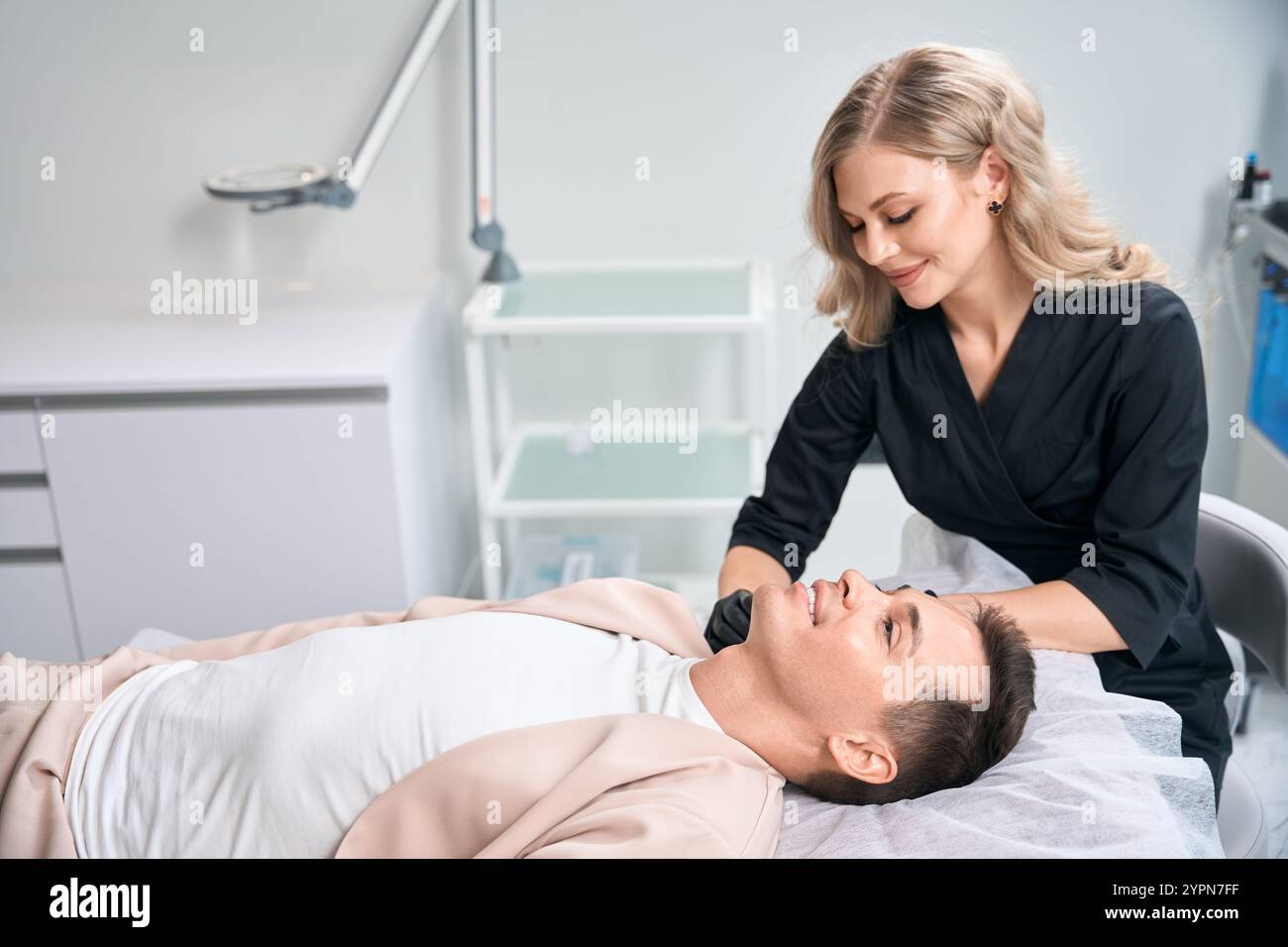 Focused woman aesthetician correcting male face contour making filler ...