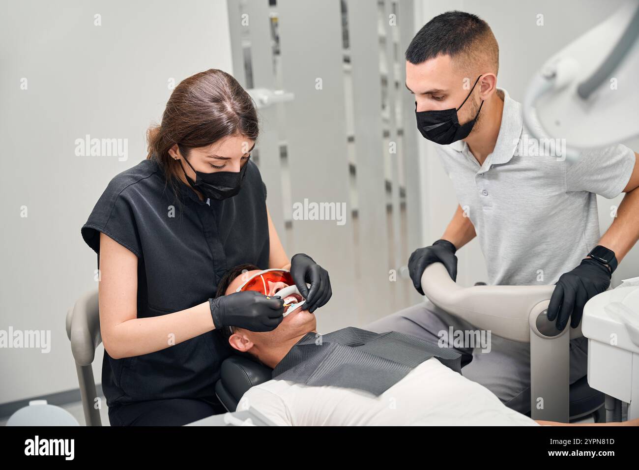 Qualified doctor applying whitening agent on male client teeth Stock ...